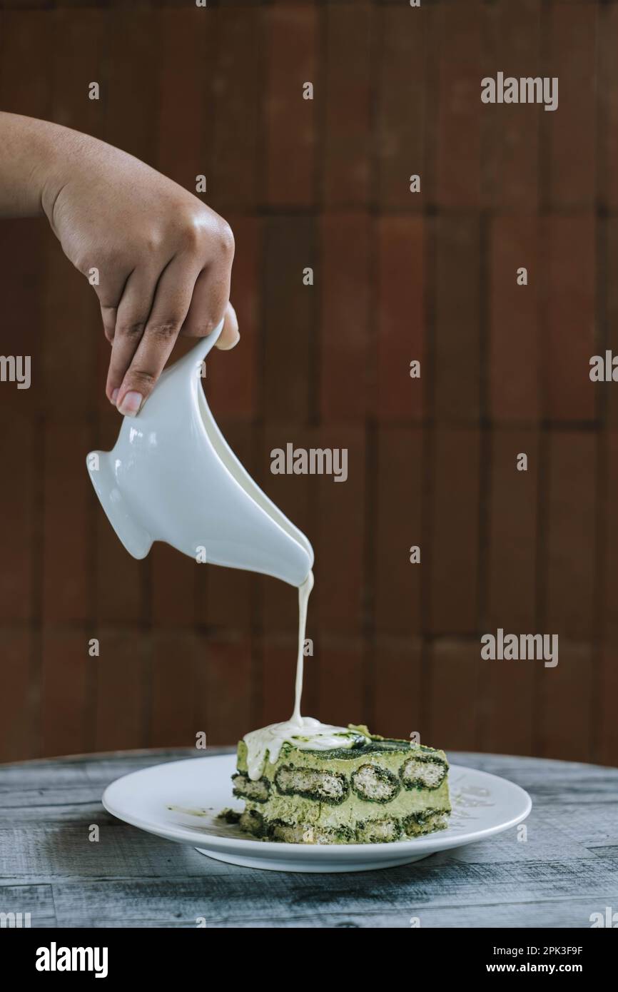 Portrait or vertical shot of pouring Creamy Custard on Japanese Matcha ...