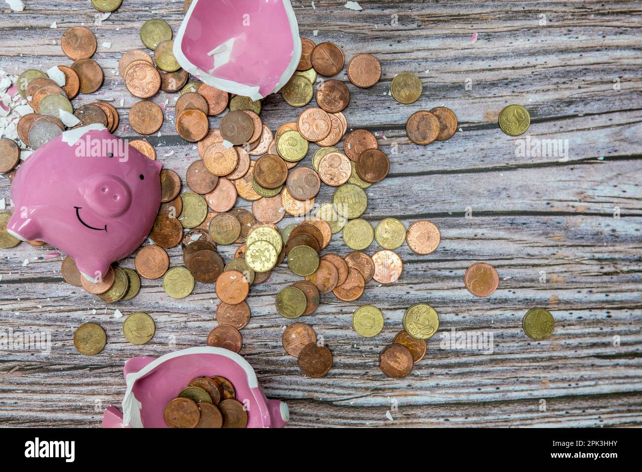 Broken piggy bank smashed into pieces with hammer, with cash and coins ...