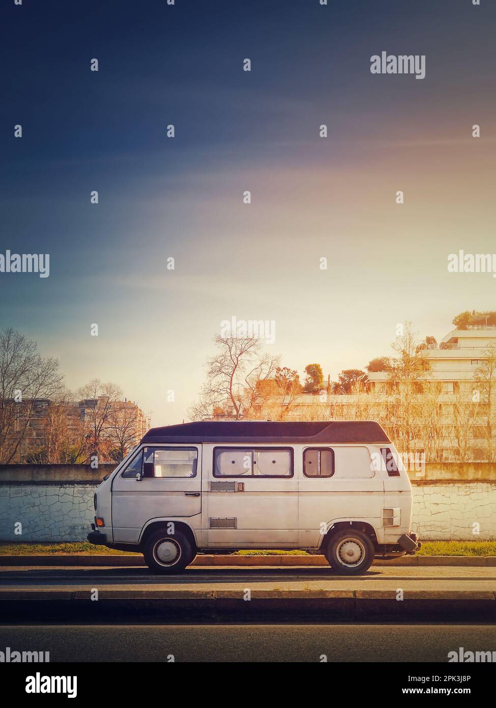 Old van parked on the edge of the street in the sunset sky background ...