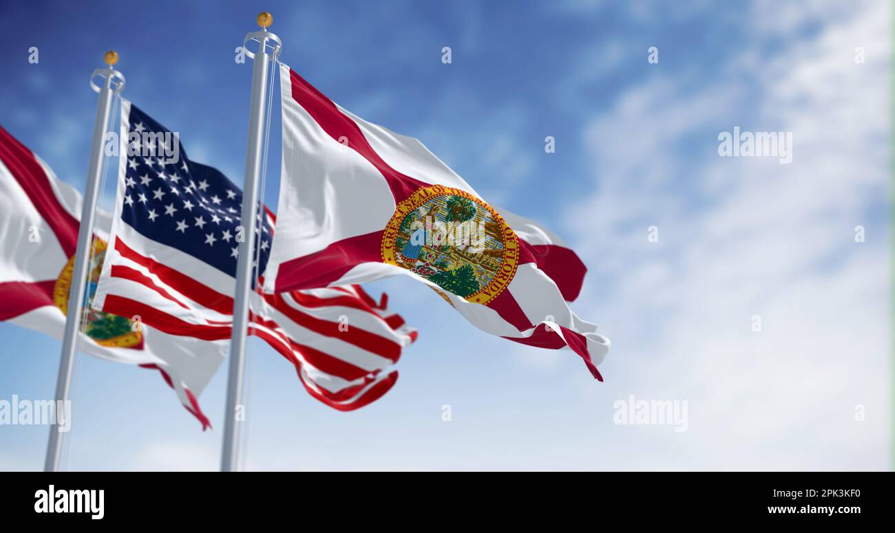 The flags of Florida and United States waving in the wind on a clear ...