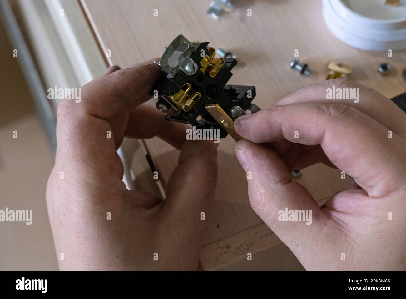 Male hands holding electrical outlet detail close-up. A repairman fixes ...