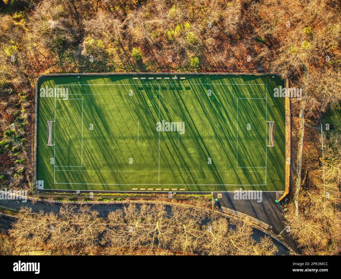 An aerial top view of an empty soccer field surrounded by lush green ...