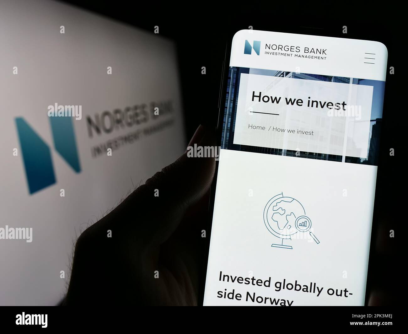 Person holding cellphone with webpage of Norges Bank Investment ...