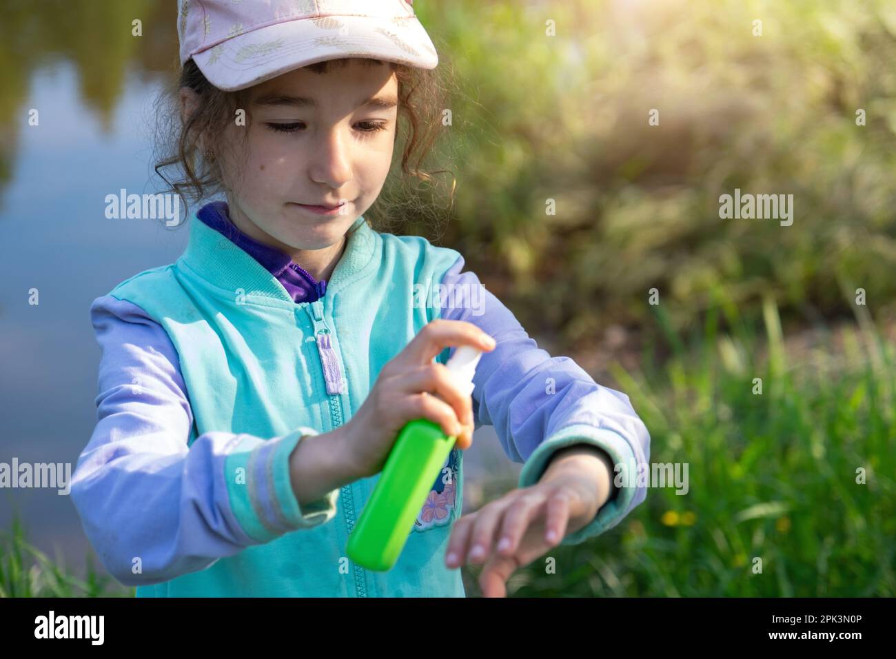 Girl sprays mosquito spray on the skin in nature that bite her hands ...