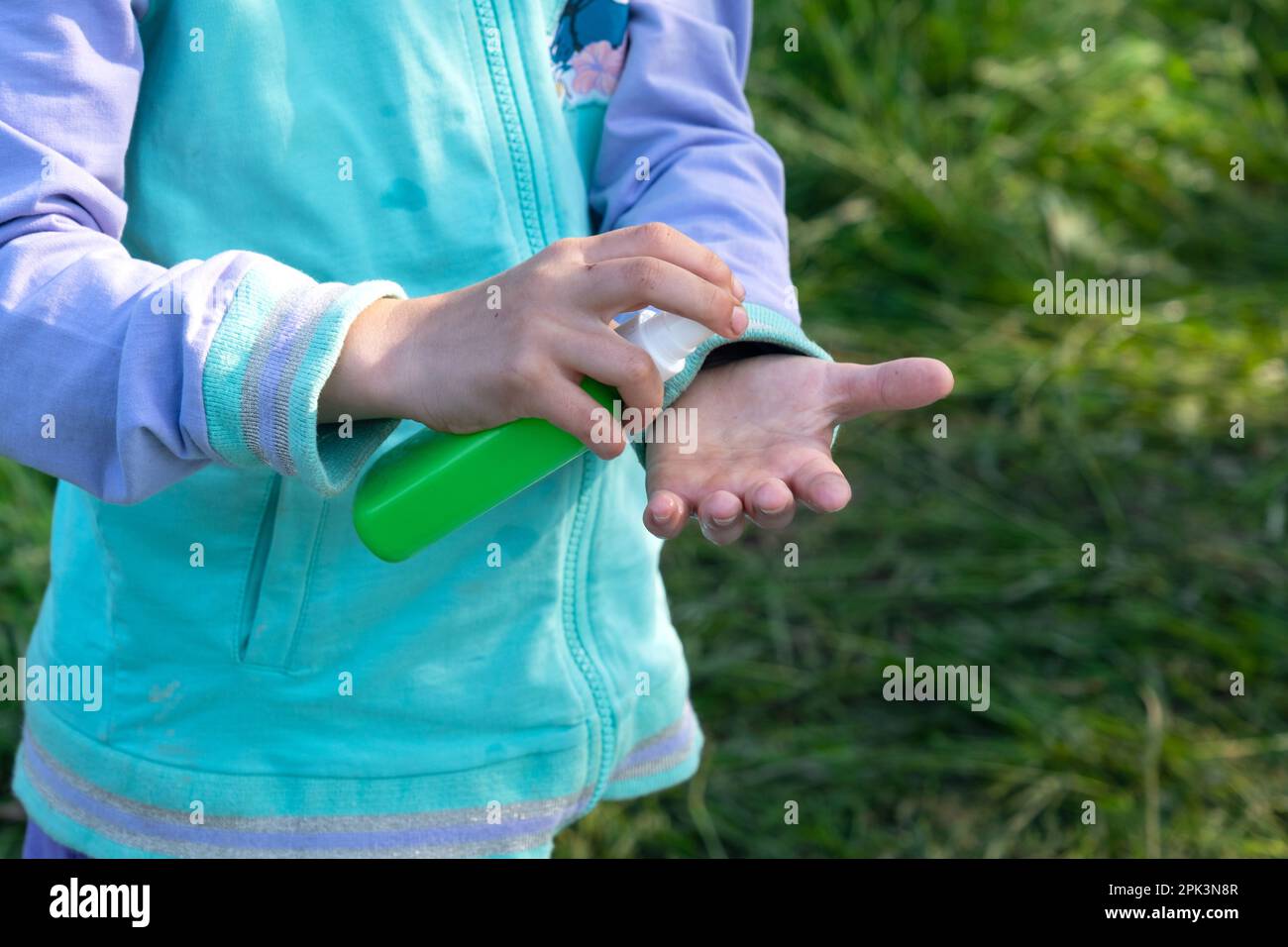 Girl sprays mosquito spray on the skin in nature that bite her hands ...