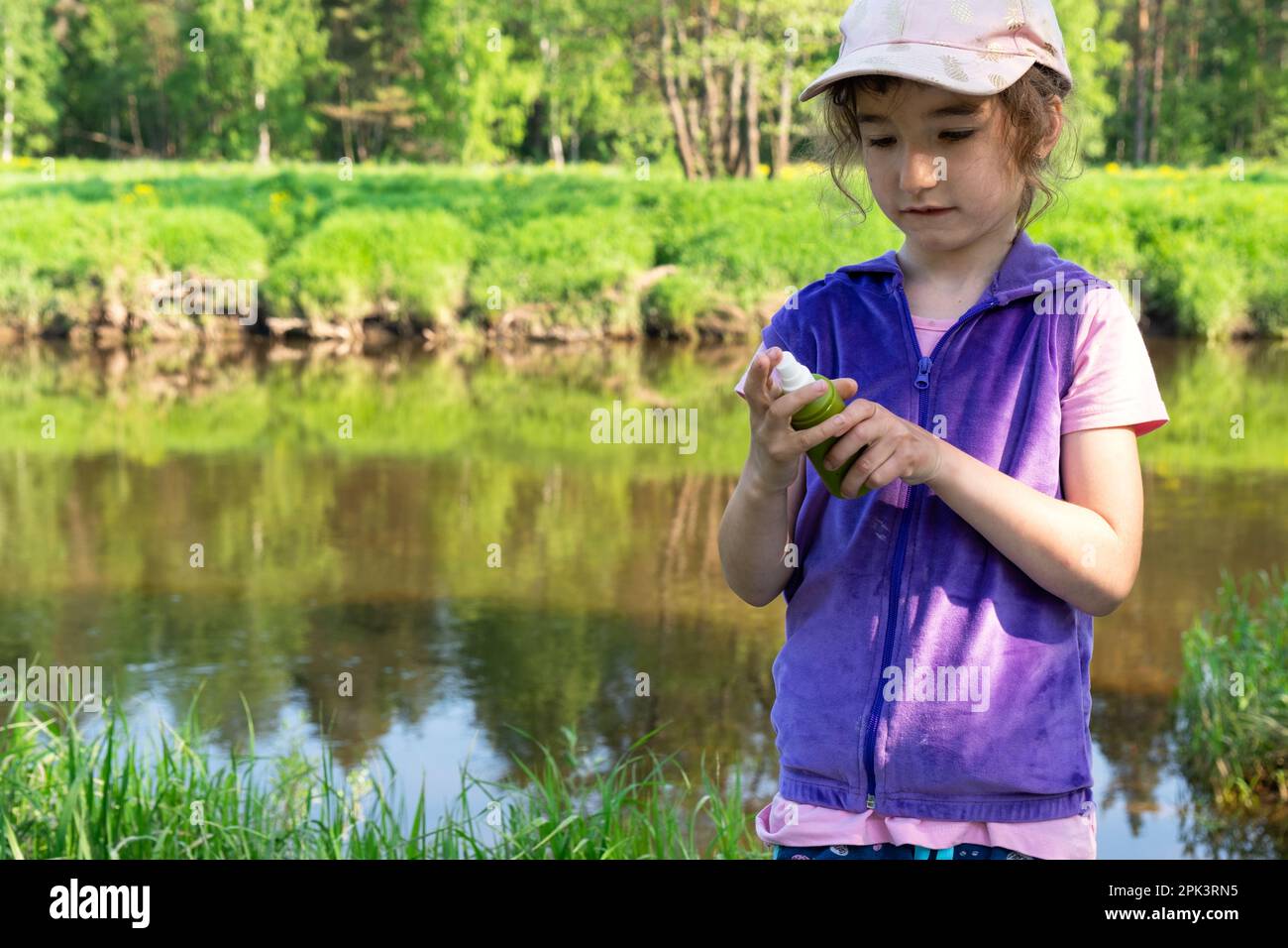 Girl sprays mosquito spray on the skin in nature that bite her hands ...