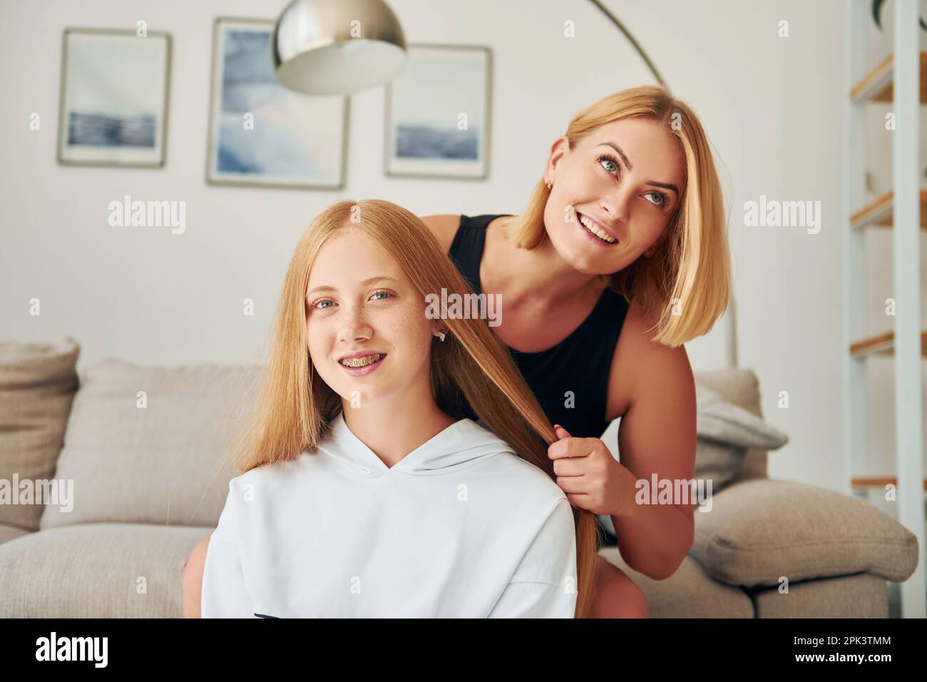 Parent helping with hair. Female teenager with her mother is at home at ...