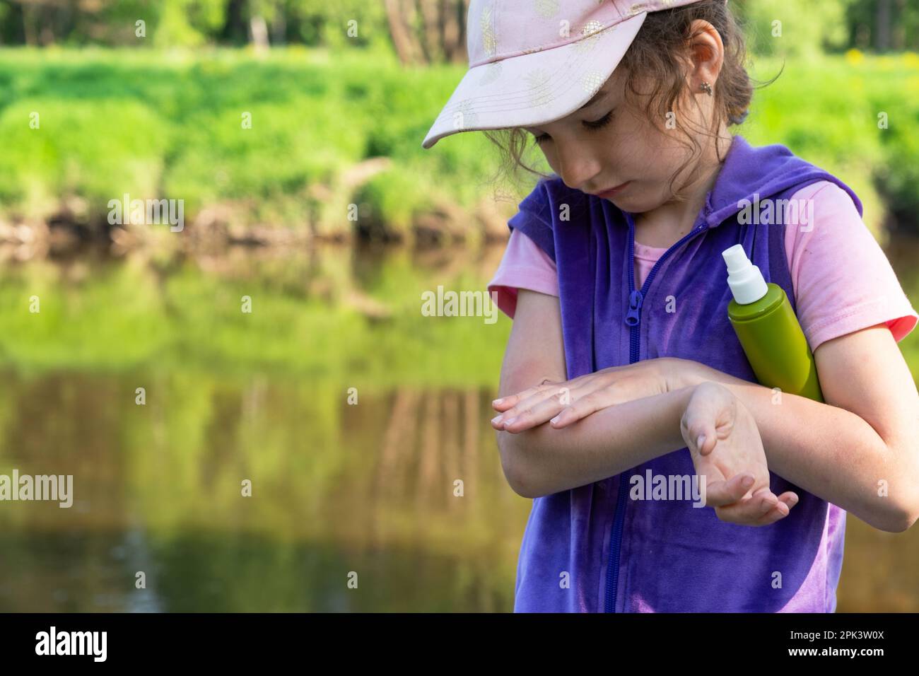 Girl sprays mosquito spray on the skin in nature that bite her hands ...