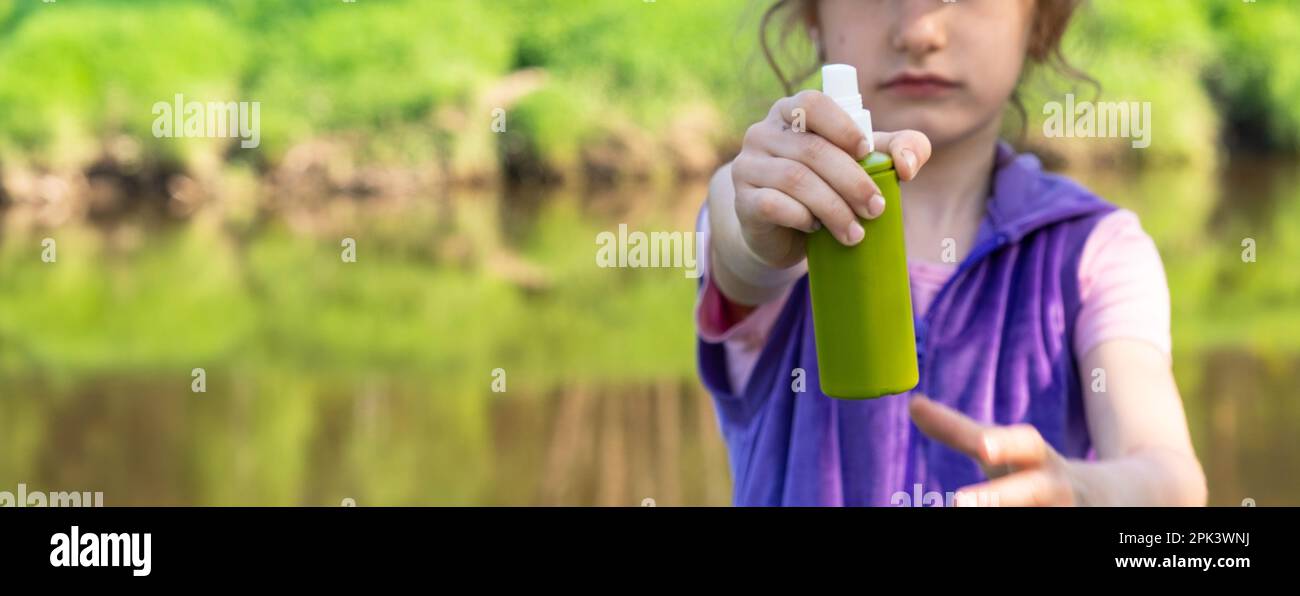 Girl sprays mosquito spray on the skin in nature that bite her hands ...