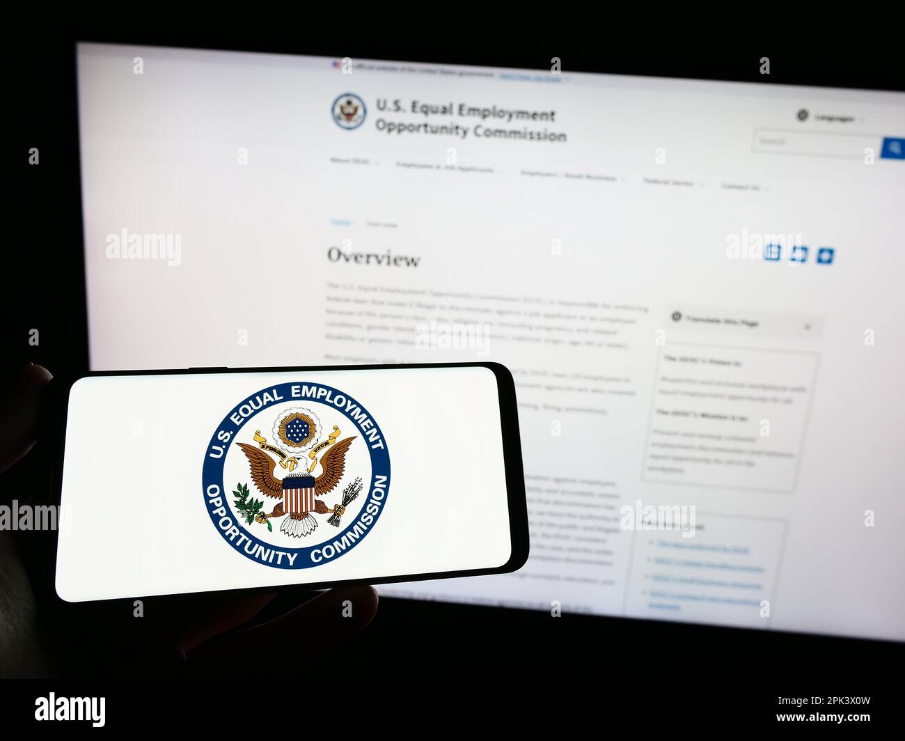 Person holding mobile phone with logo of Equal Employment Opportunity ...