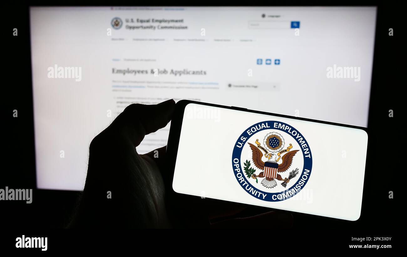 Person holding smartphone with logo of Equal Employment Opportunity ...