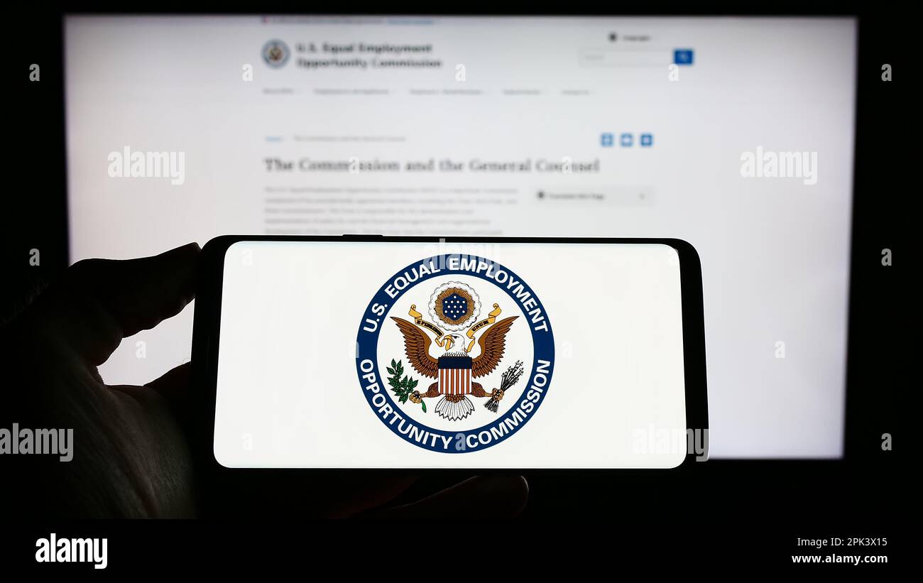 Person holding cellphone with logo of Equal Employment Opportunity ...