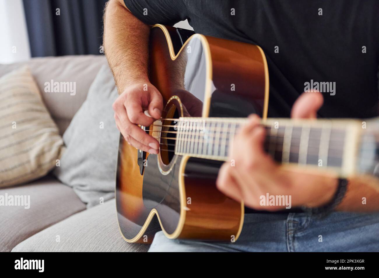 Playing the instrument. Man in casual clothes and with acoustic guitar ...
