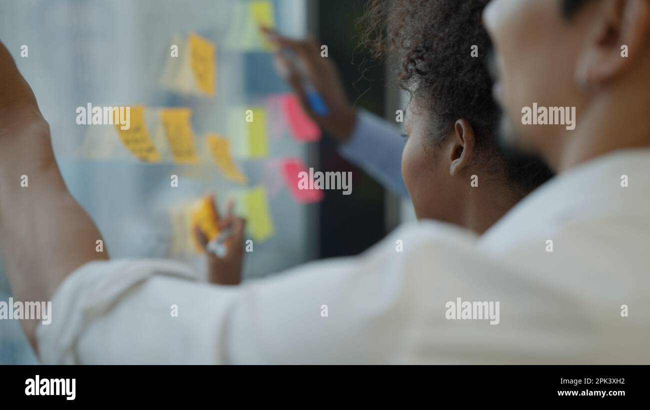 Business people taking reminder post-it notes on board during ...