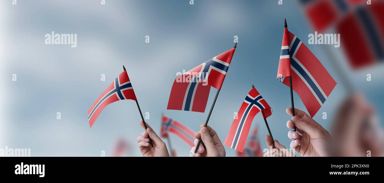A group of people holding small flags of the Norway in their hands ...