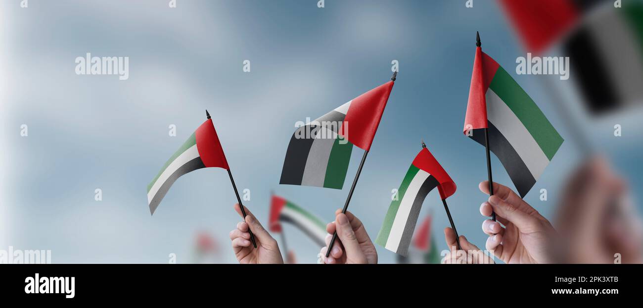A group of people holding small flags of the Arab Emirates in their ...