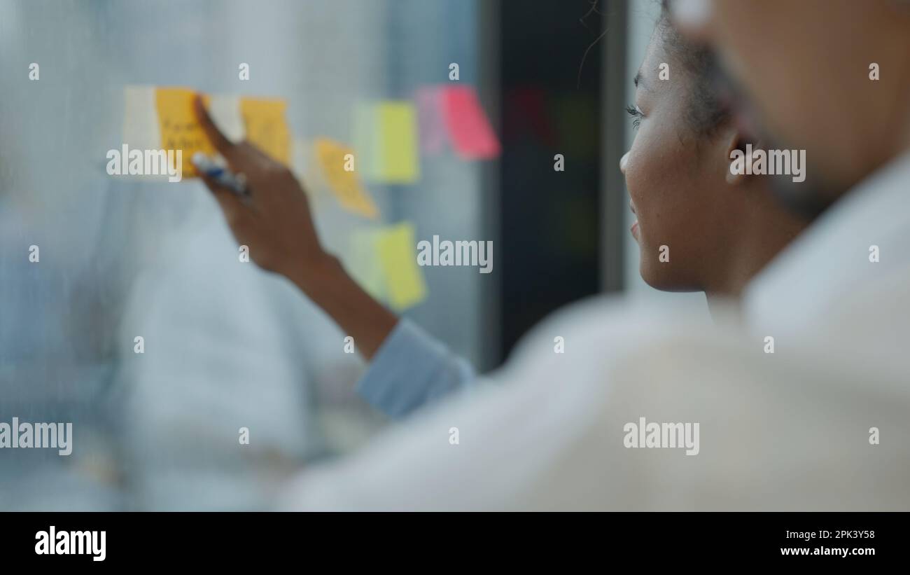 Business people taking reminder post-it notes on board during ...