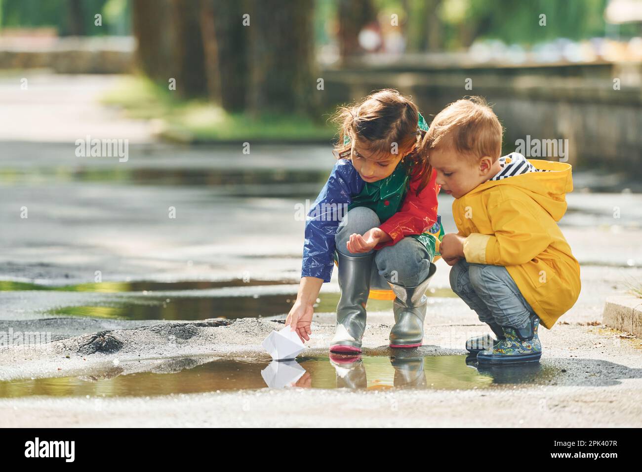 In the puddle. Kids having fun outdoors in the park after the rain ...