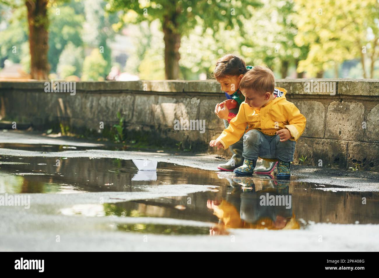 In the puddle. Kids having fun outdoors in the park after the rain ...
