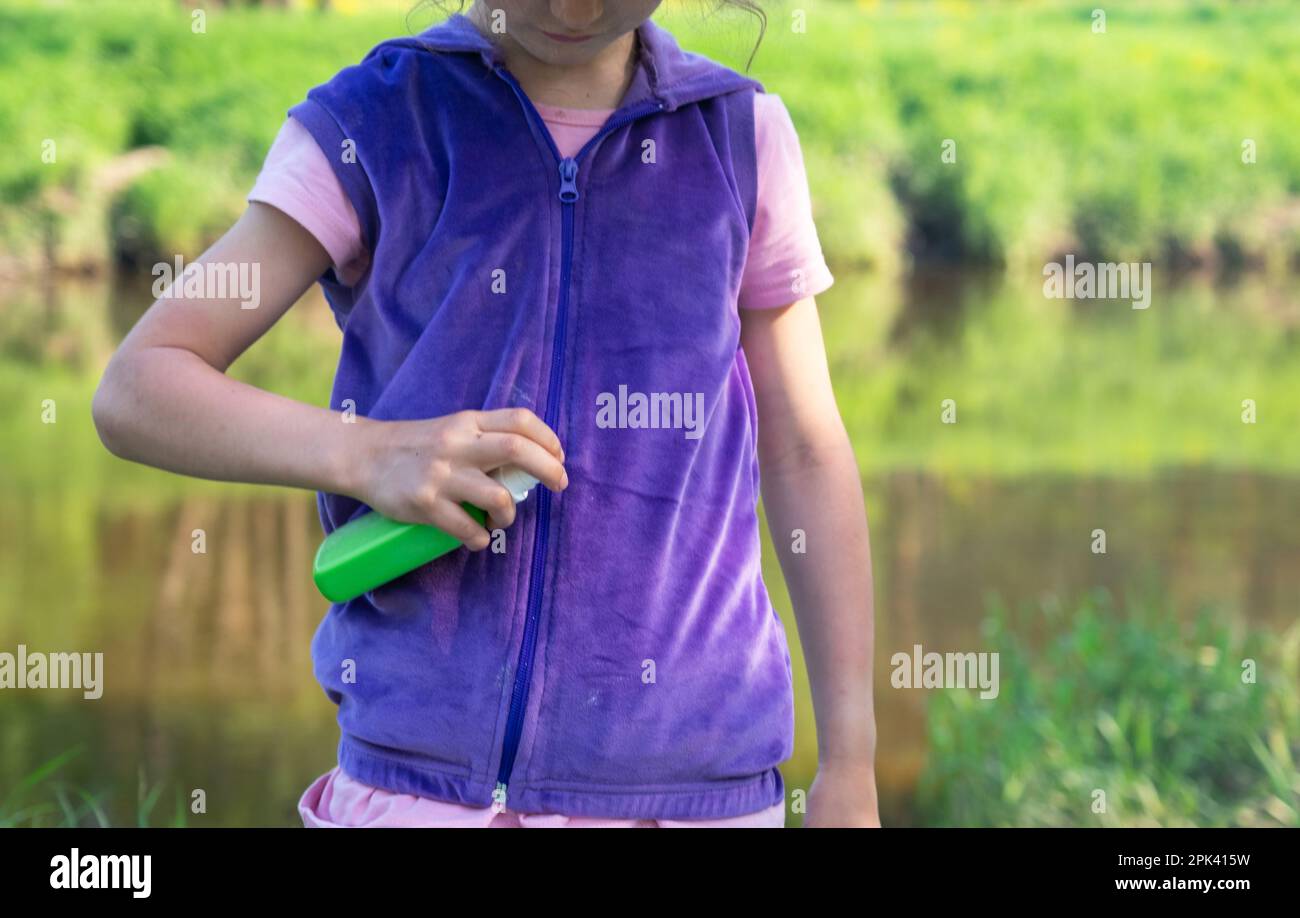 Girl sprays mosquito spray on the skin in nature that bite her hands ...