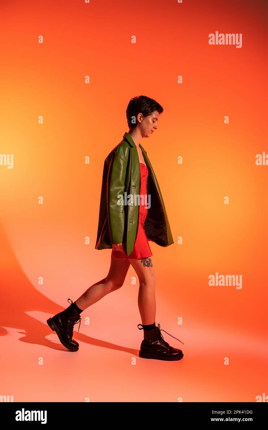 side view of slender woman in black boots and green leather jacket ...