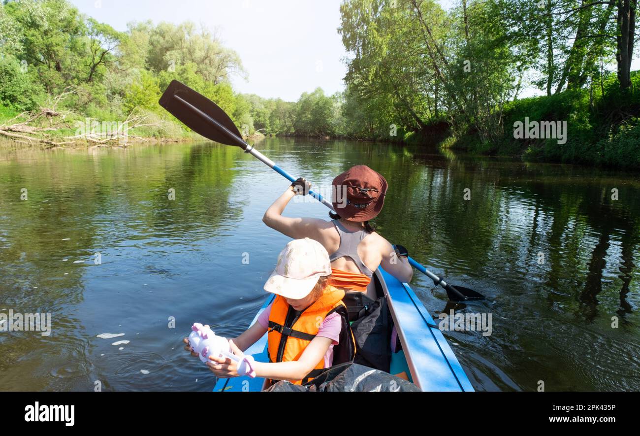 Family kayak trip. Mom and daughter rowing a boat on the river, a water ...