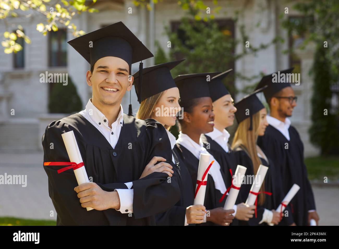 Happy graduate man in graduation gown and cap with diploma posing for ...
