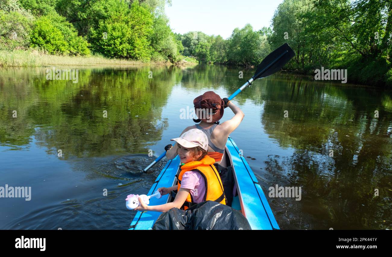 Family kayak trip. Mom and daughter rowing a boat on the river, a water ...