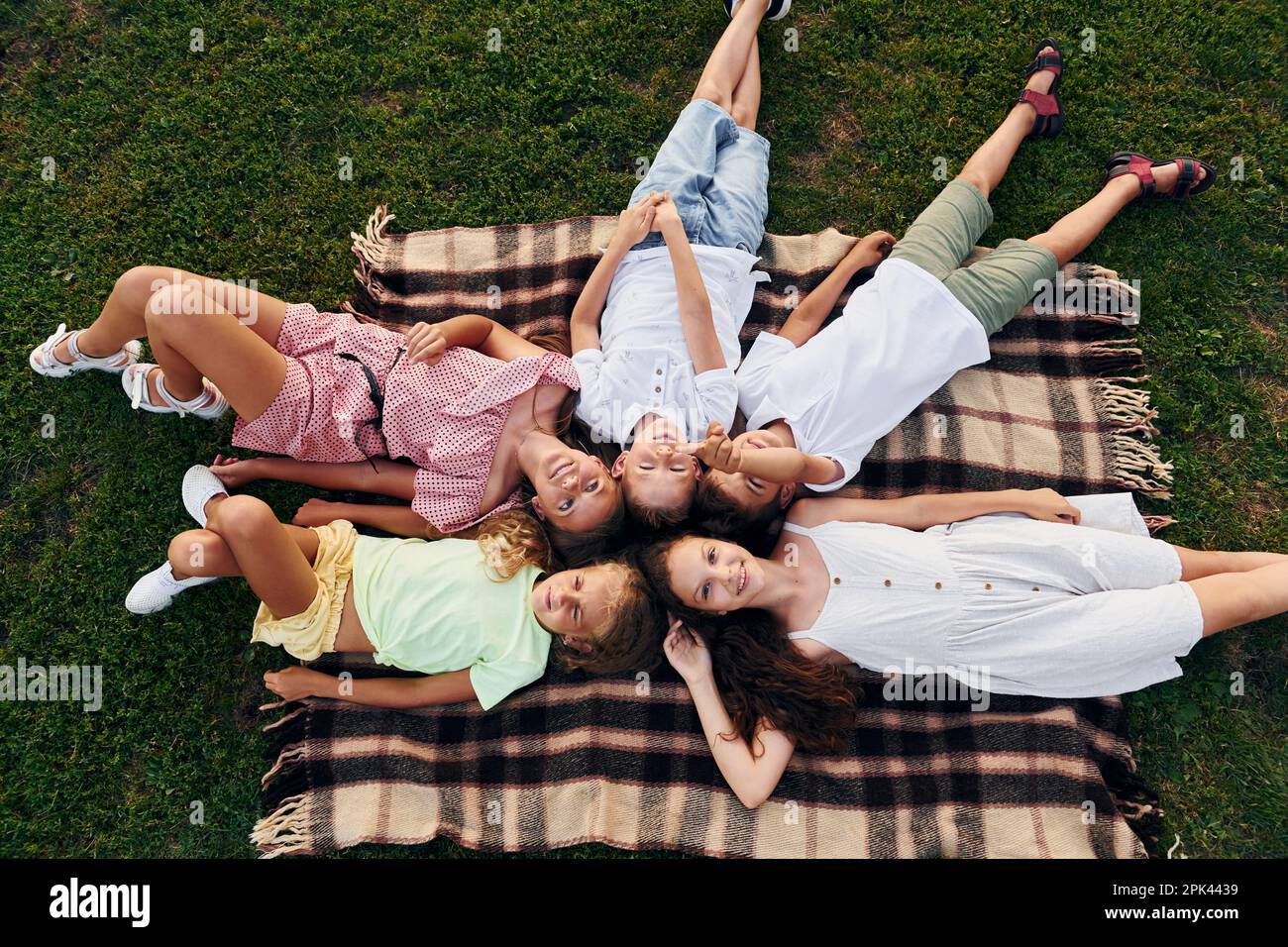 Having a rest and laying down. Group of happy kids is outdoors on the ...