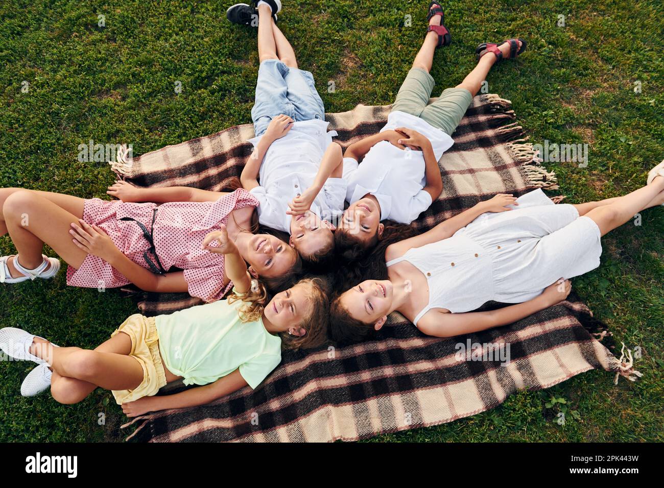 Having a rest and laying down. Group of happy kids is outdoors on the ...
