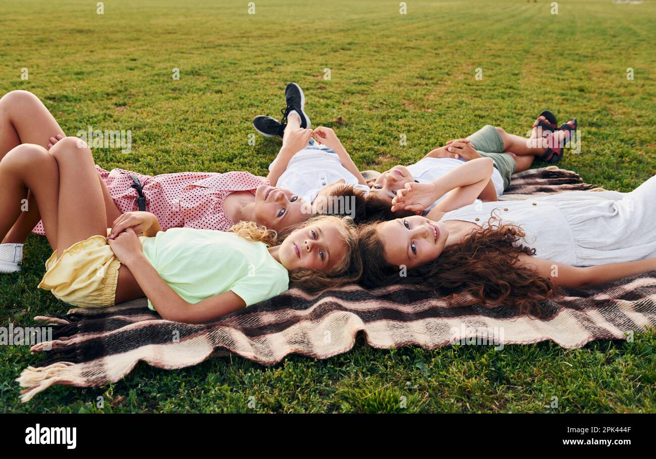 Having a rest and laying down. Group of happy kids is outdoors on the ...