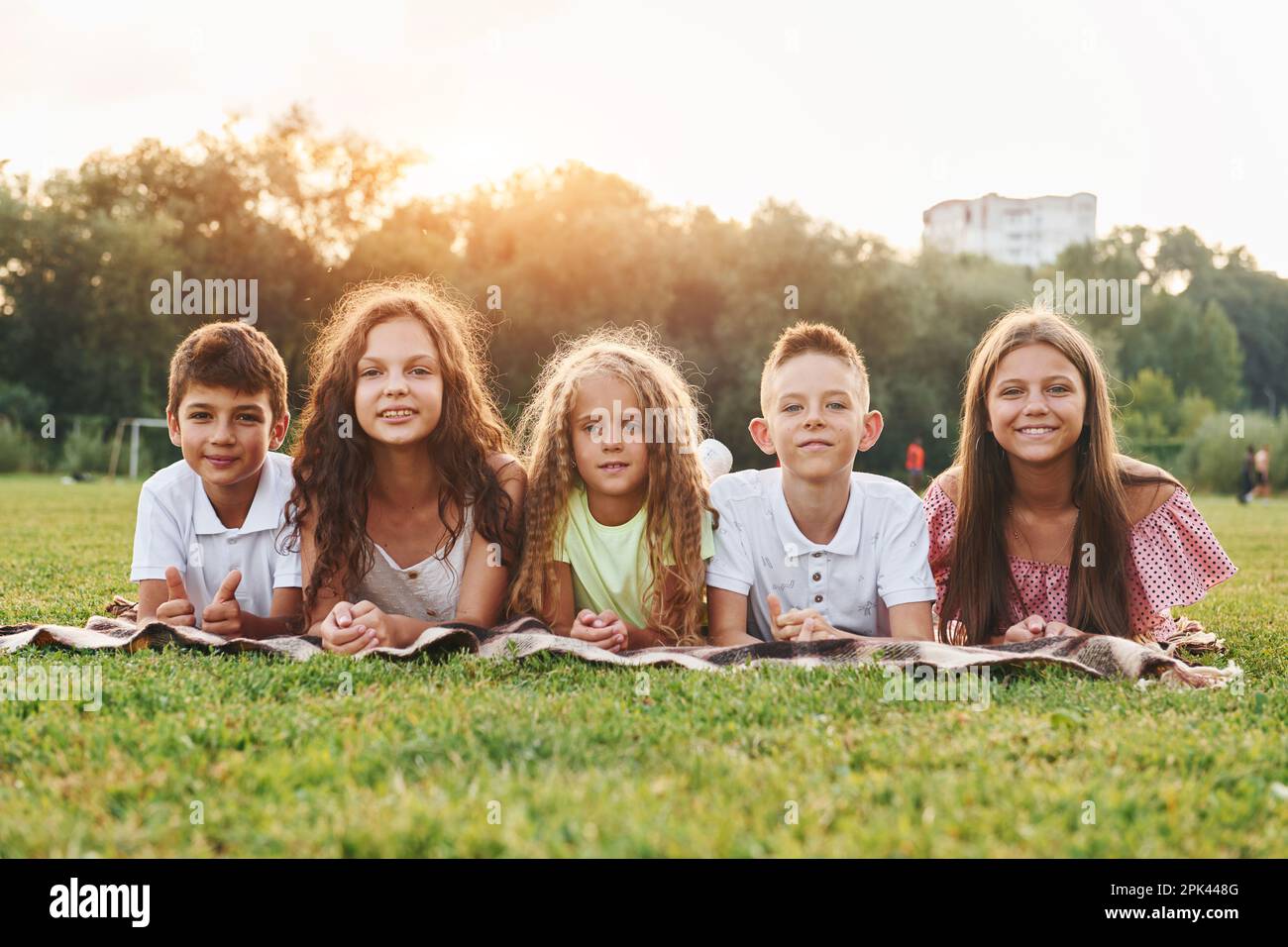 Front view. Group of happy kids is outdoors on the sportive field at ...