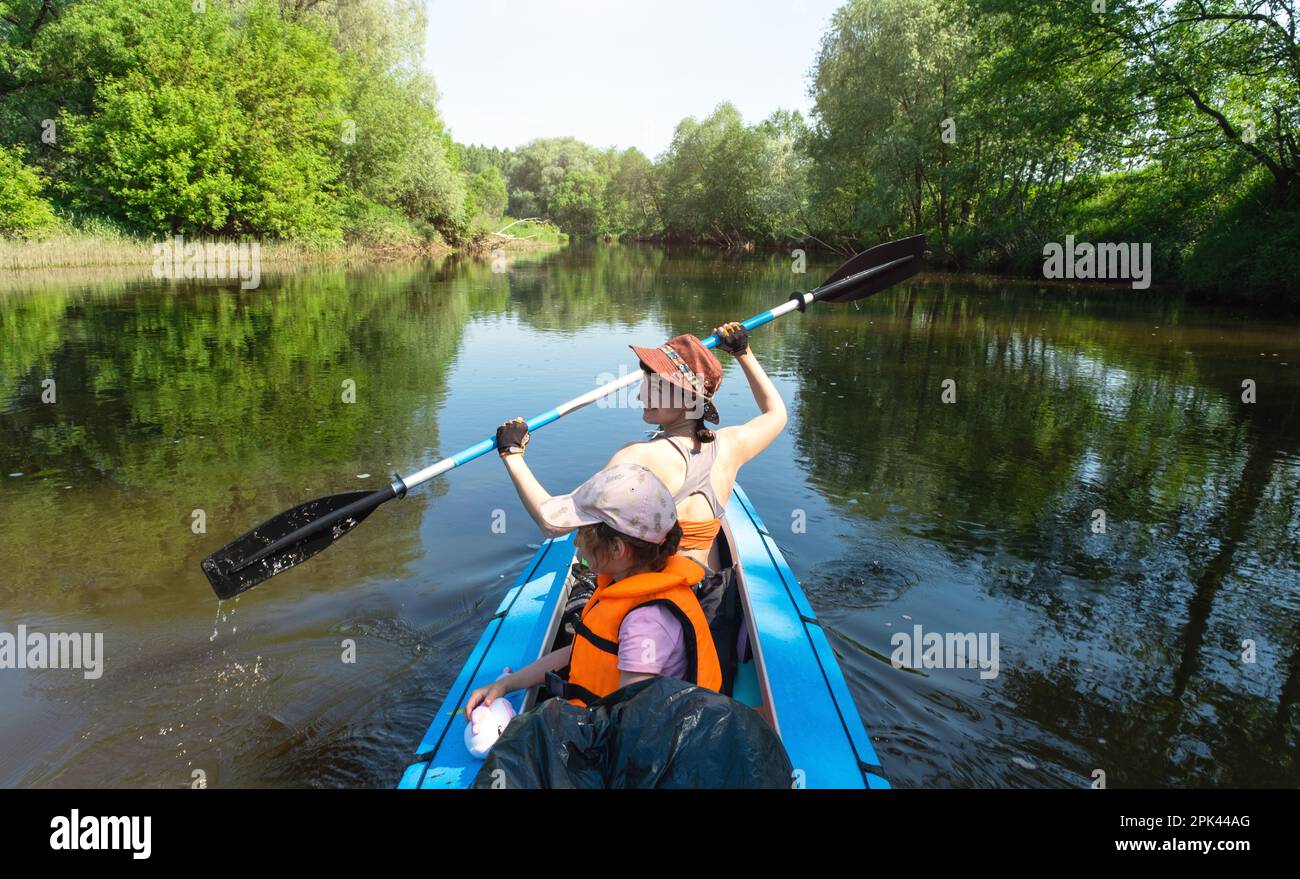 Family kayak trip. Mom and daughter rowing a boat on the river, a water ...