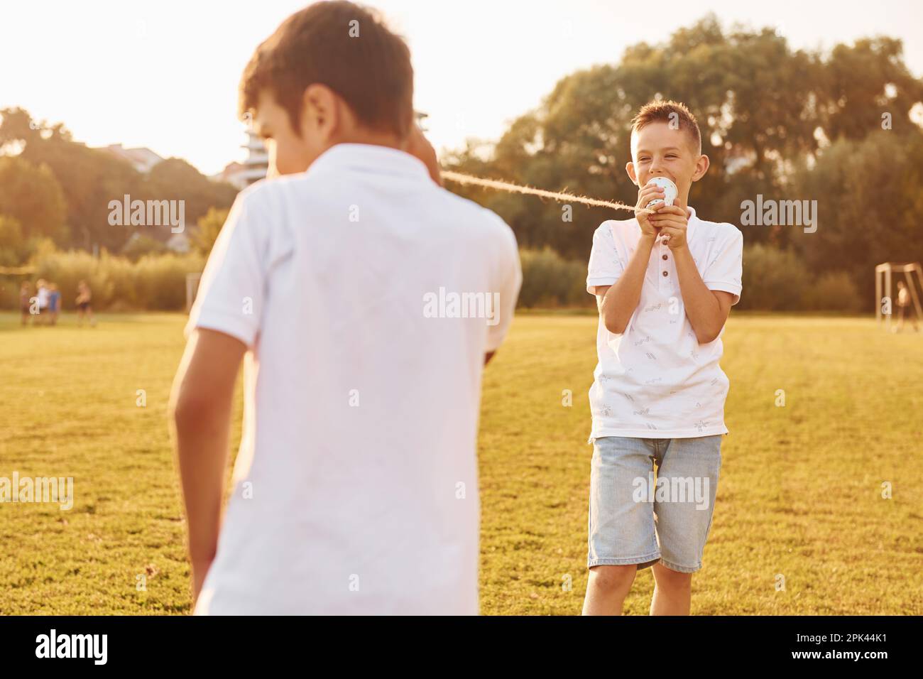 Two boys having fun by using tin can telephone on the sportive field Stock Photo - Alamy
