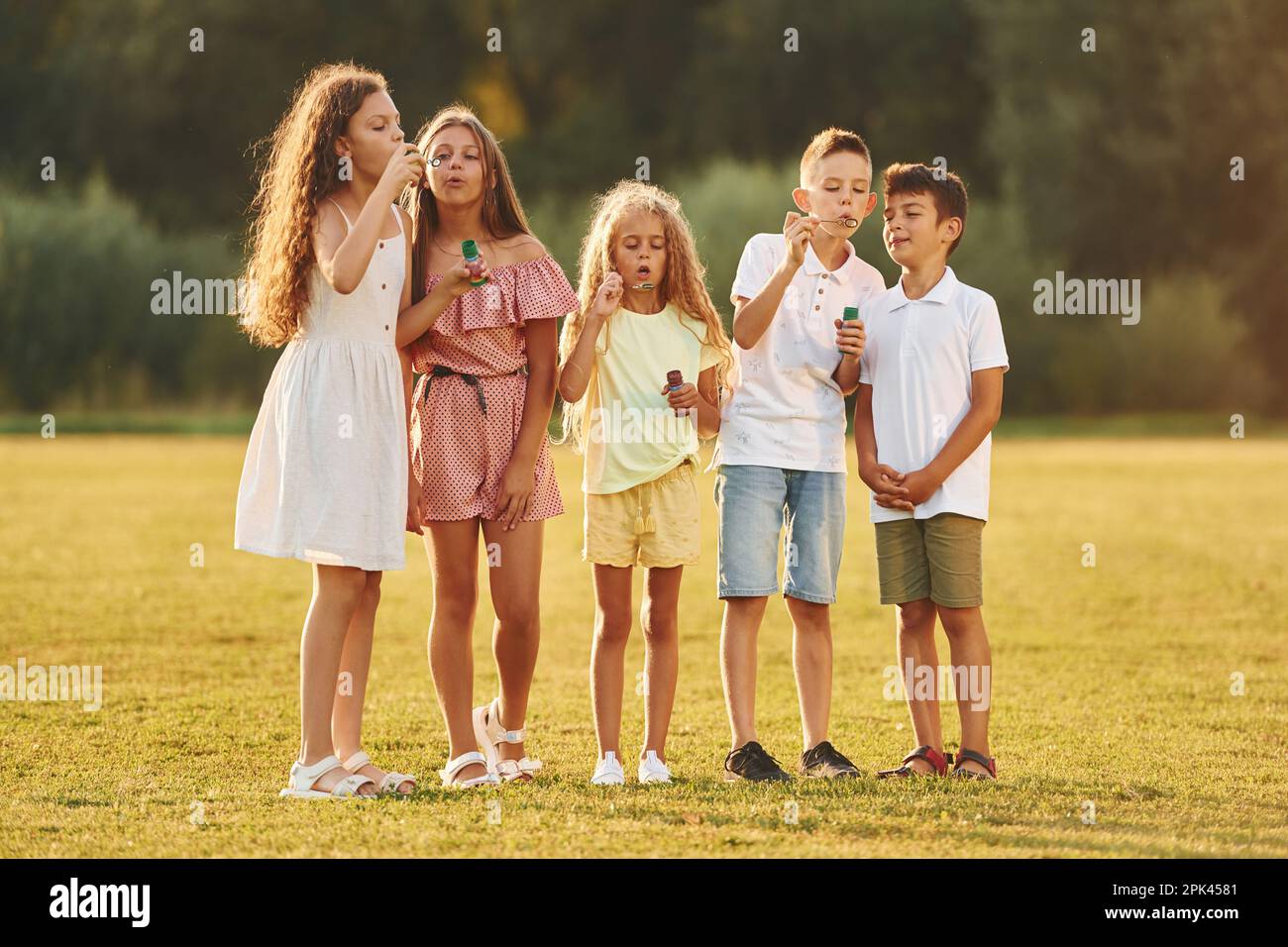 Beautiful sunlight. Group of happy kids is outdoors on the sportive ...