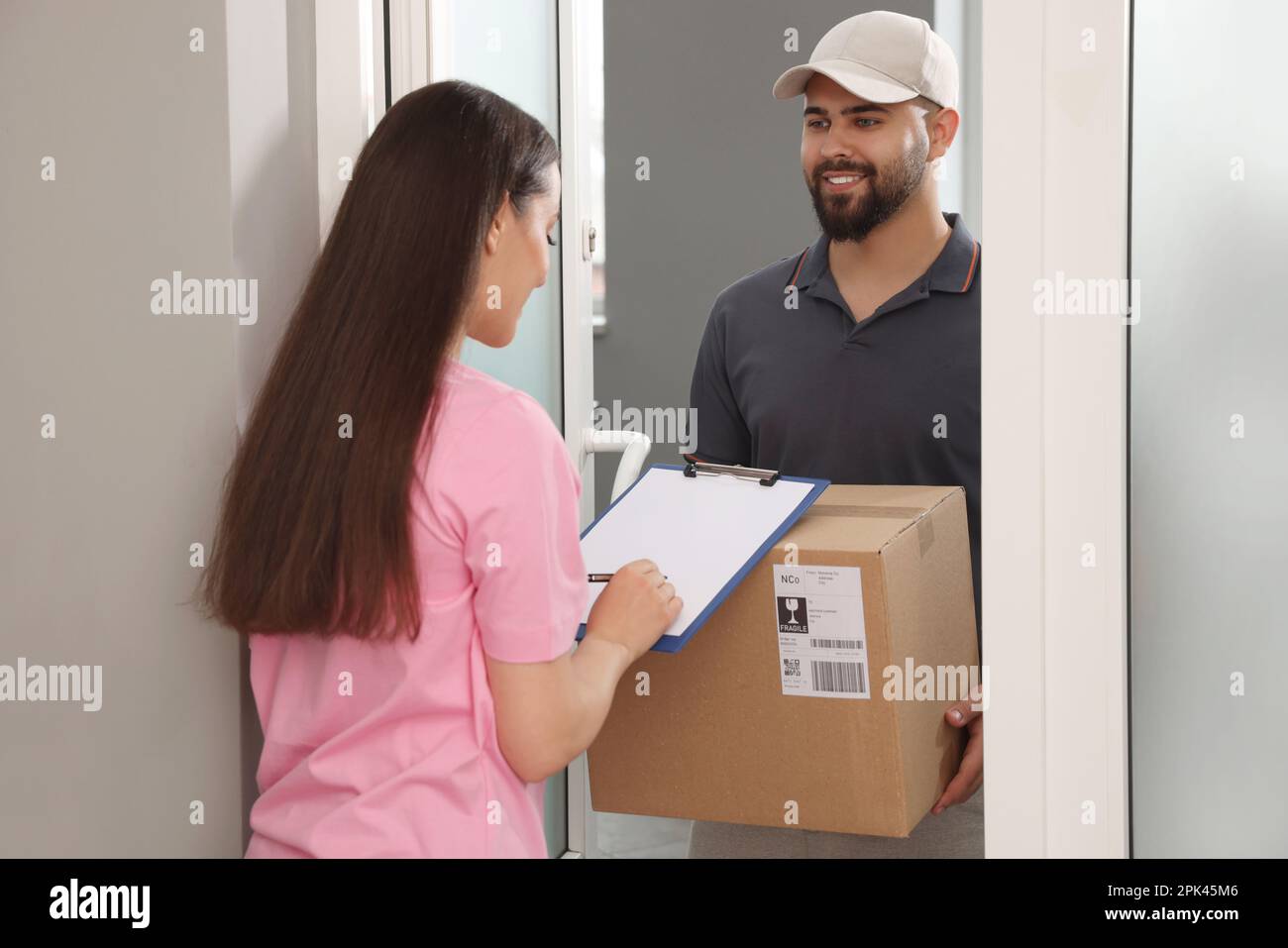 Woman signing for delivered parcel at home Stock Photo - Alamy