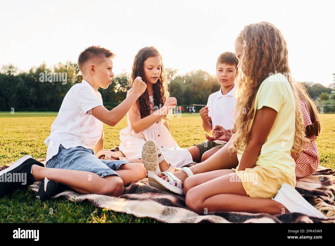 Playing games. Group of happy kids is outdoors on the sportive field at ...