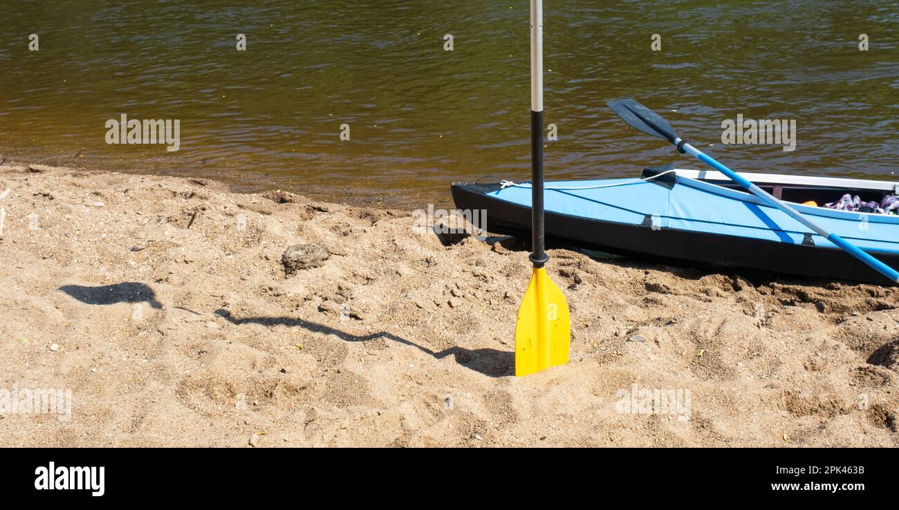 Tourist canoes with paddles stand on the river coast in summer on a ...