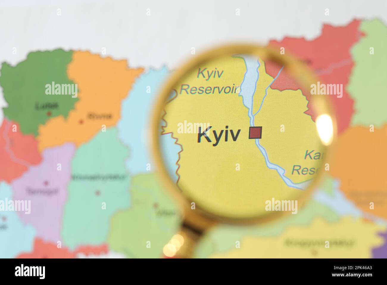 Golden magnifying glass above Kyiv region on map of Ukraine, closeup ...