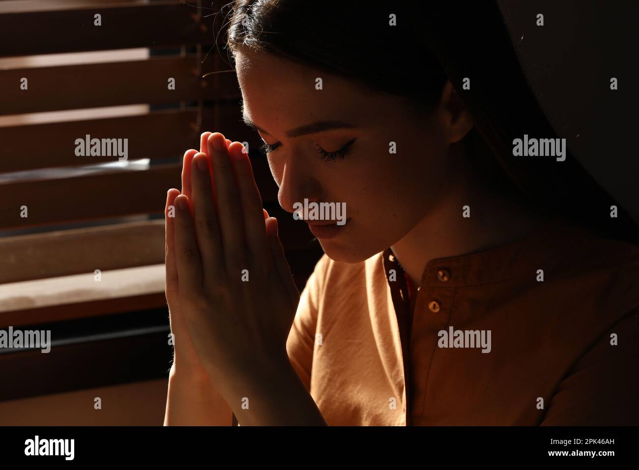 Religious young woman with clasped hands praying indoors, closeup Stock ...