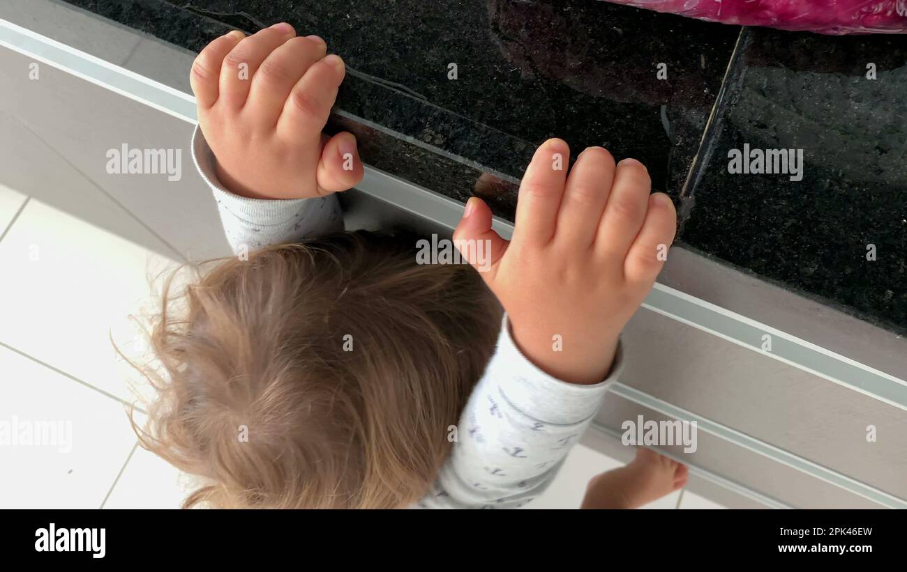 Baby toddler holding into the edge of a table, disobedient child ...