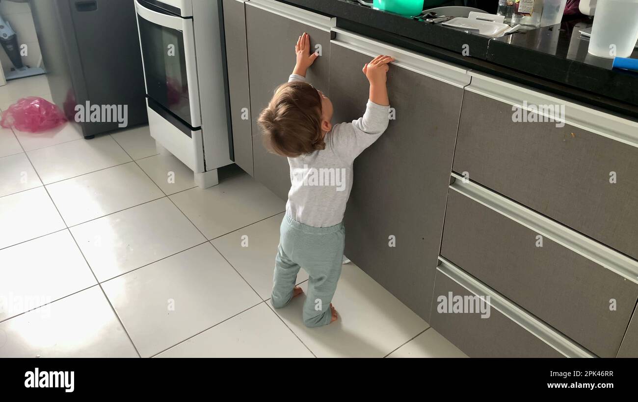 Baby toddler opening kitchen cabinets. infant on tippy toes reaching ...