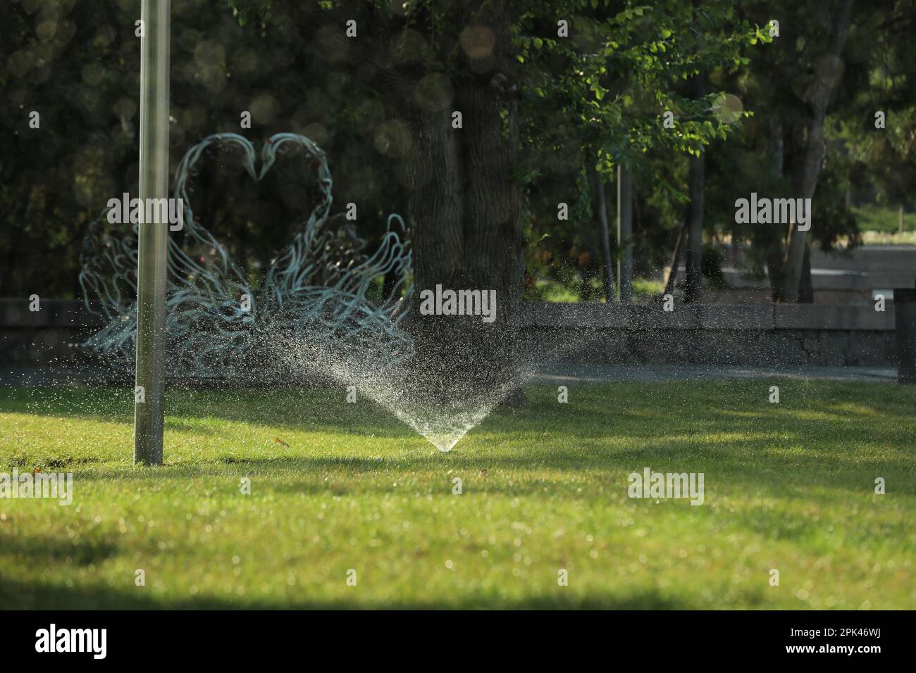 Automatic sprinkler watering green grass in park. Irrigation system ...