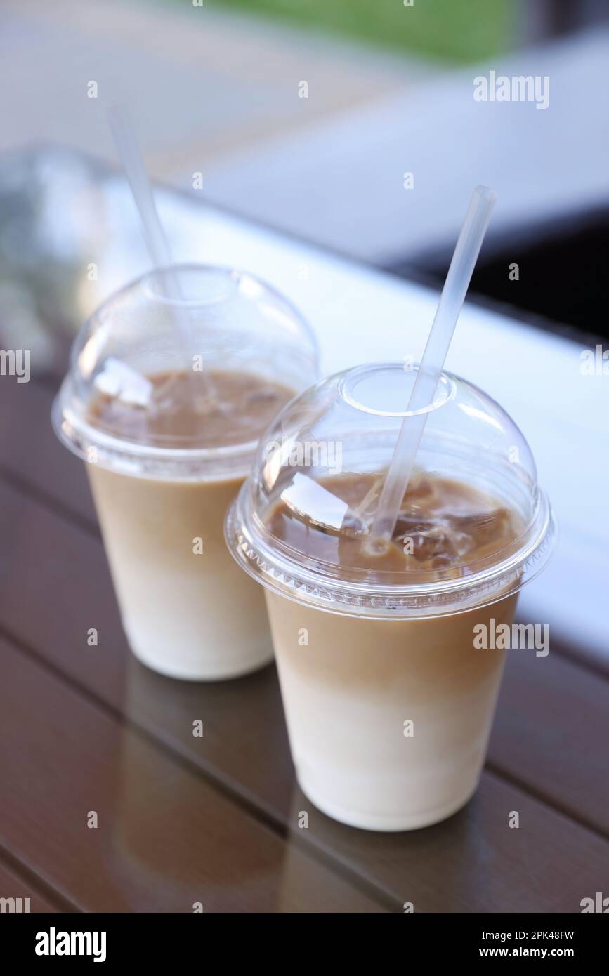 Plastic takeaway cups of delicious iced coffee on table in outdoor cafe ...
