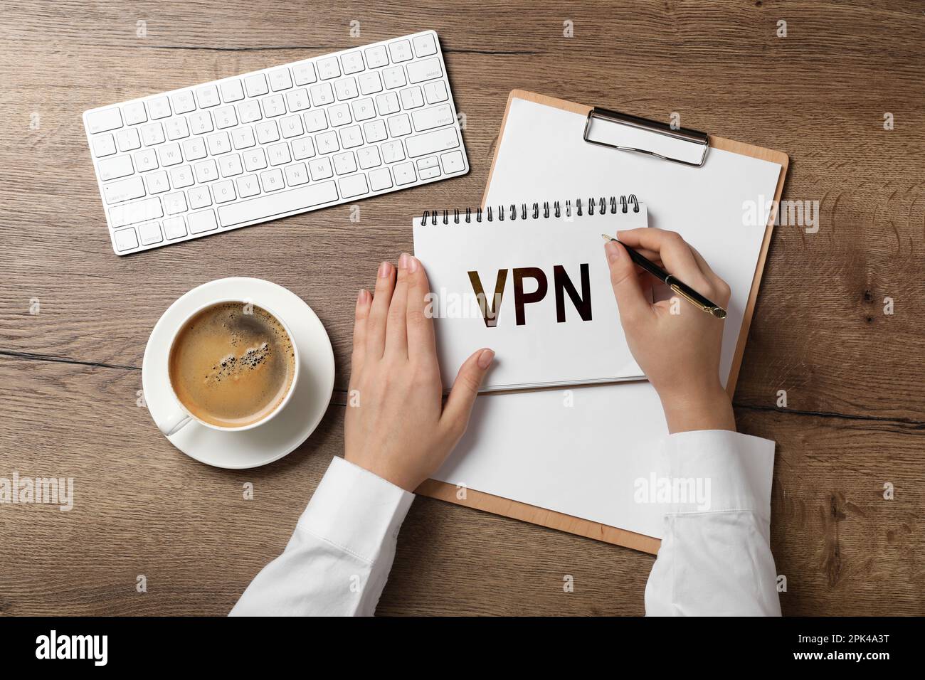 Woman writing acronym VPN in notebook at wooden table, top view. Secure ...