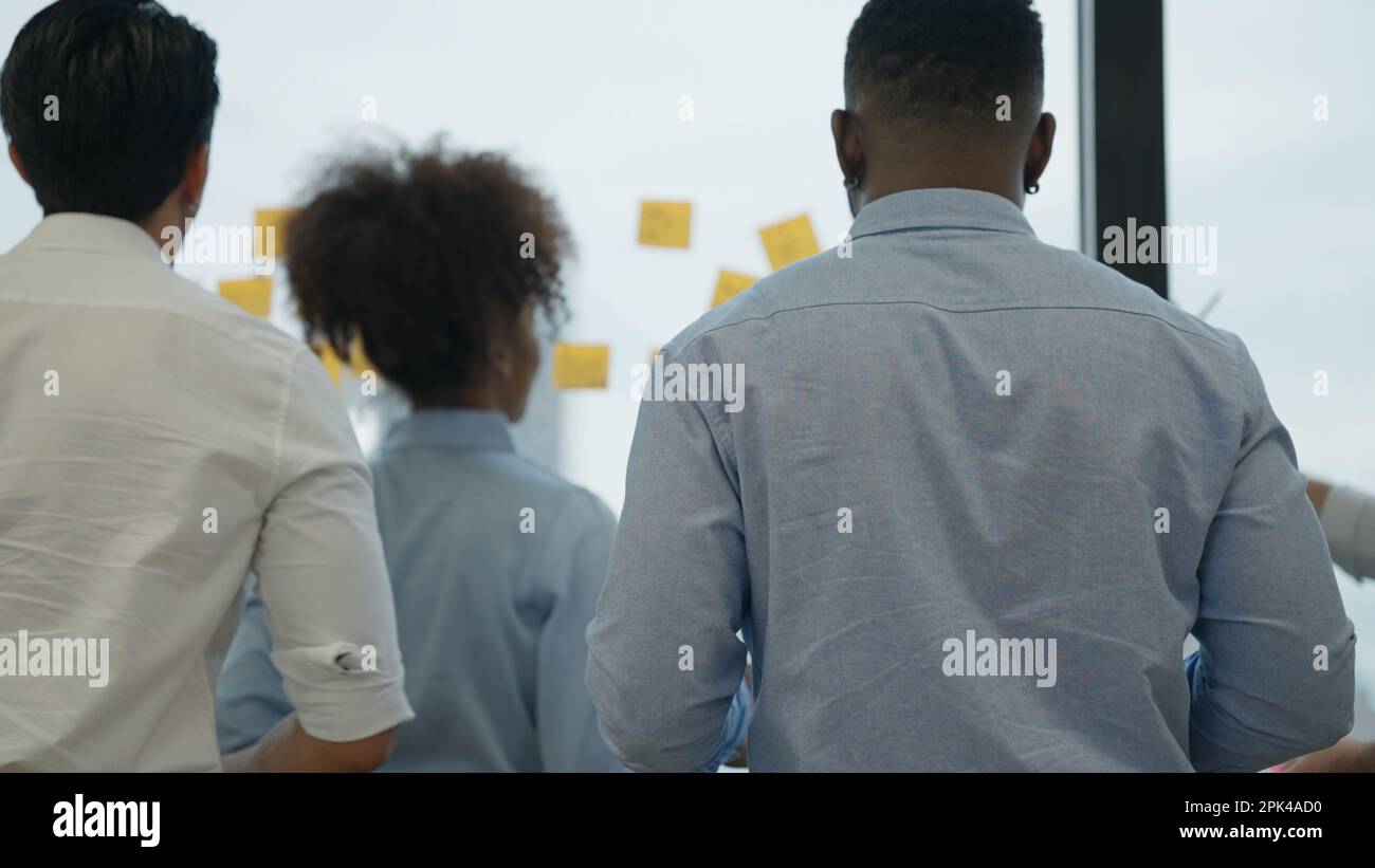 Business people taking reminder post-it notes on board during ...