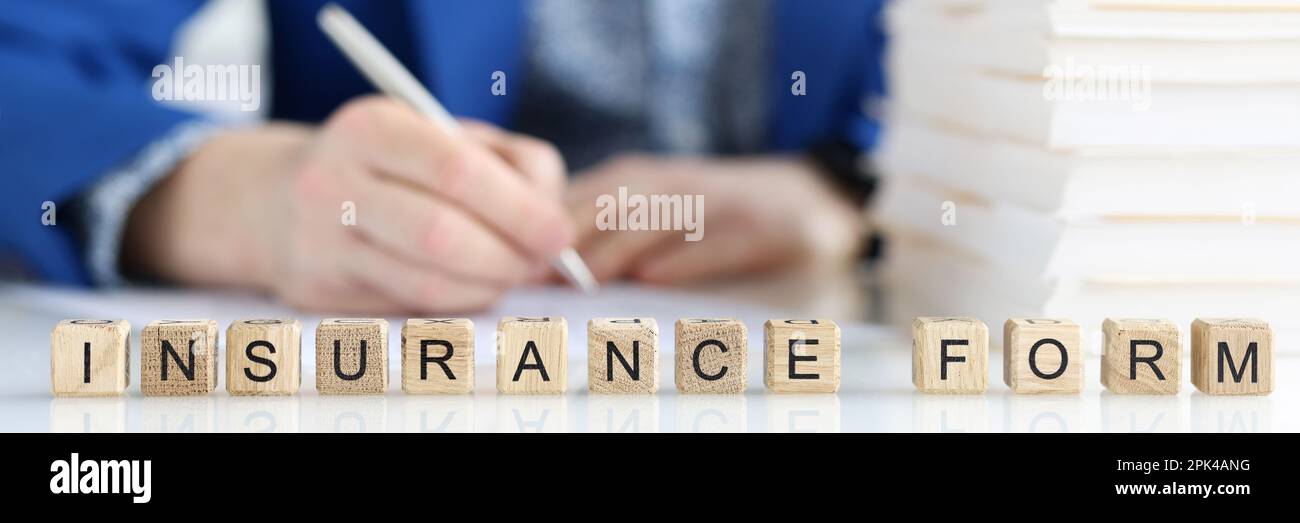 Man filling insurance claim form, word collected of wooden cubes Stock ...