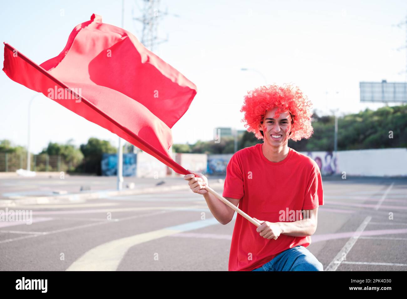 Fan with a wig and a flag in the color of his team to support them ...