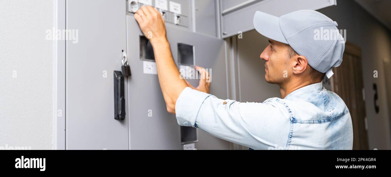 Young smiling electrician doing his work, electrical panel Stock Photo ...