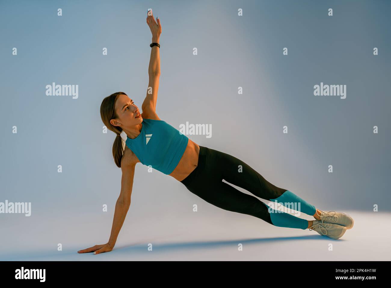 Healthy sporty woman doing side plank exercises on studio background ...